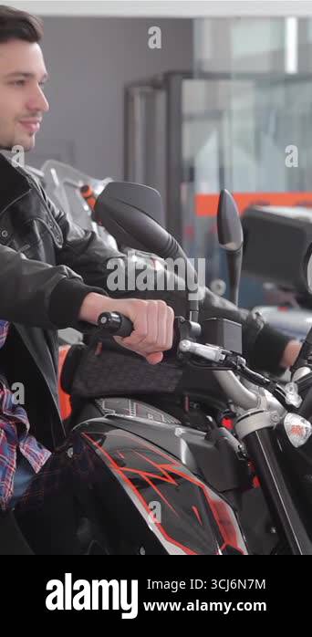 A stylish Caucasian man sits confidently on a sleek black motorcycle ...