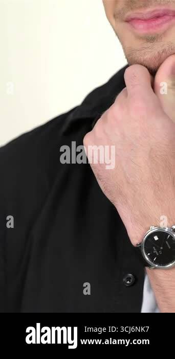 A dapper young man with a captivating smile gently holds his chin ...