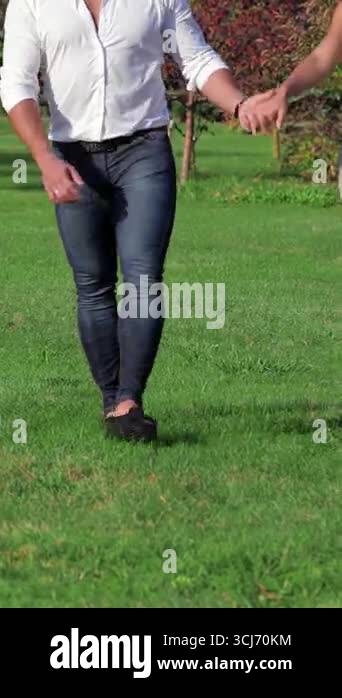 A loving husband and his pregnant wife stroll hand in hand across a ...