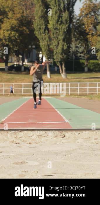A determined Caucasian male athlete sprints down the vibrant track ...