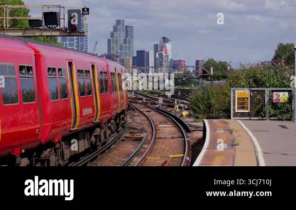 LONDON, UK - AUGUST 8, 2025 - Red train leaving a London station ...