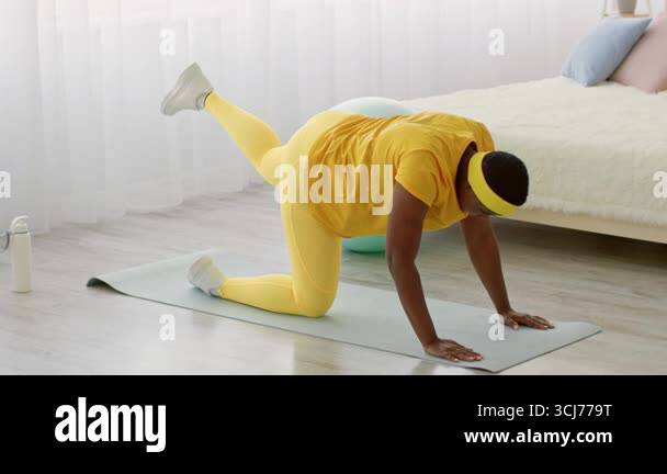 A plus size African American woman exercises at home, wearing bright ...