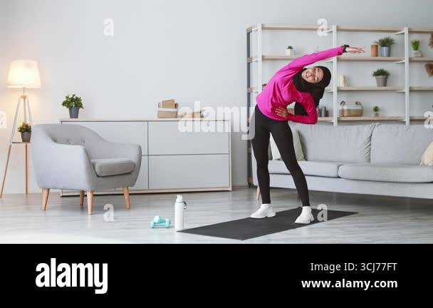 A young Middle Eastern woman practices stretching exercises in her ...