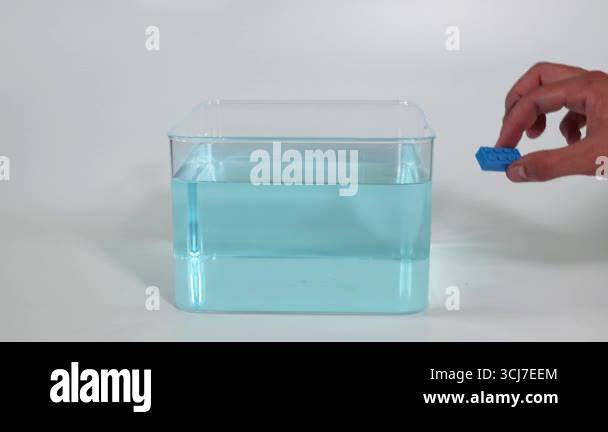 Dropping blue blocks into a water-filled container Stock Video Footage ...