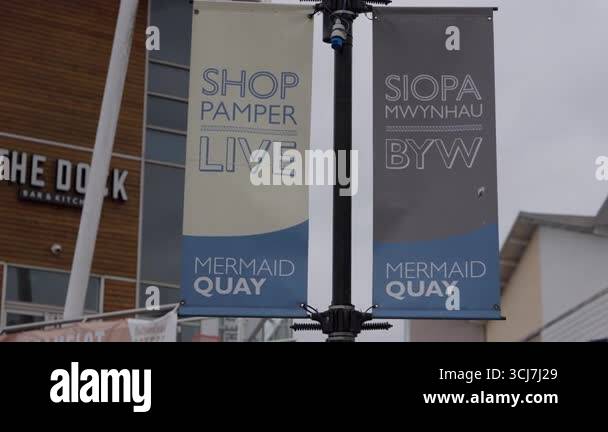 CARDIFF, UK - AUGUST 8, 2025 - Bilingual banners promoting shopping and ...