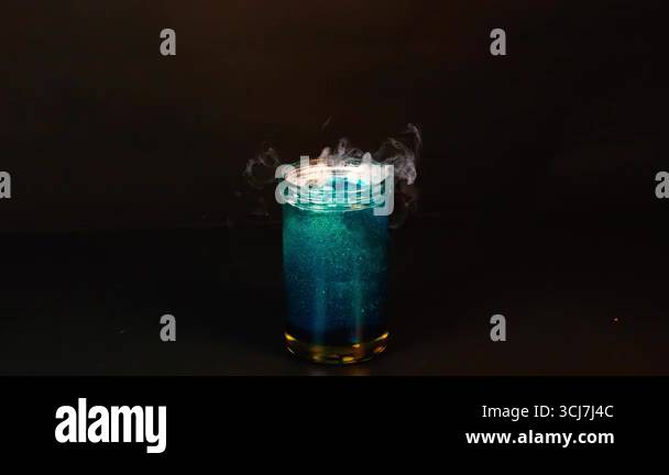 A beaker with blue liquid and dry ice creates a smoky, bubbling effect ...