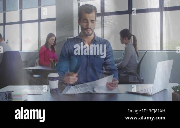 Male data analyst flipping pages at desk, updating laptop with overlay ...