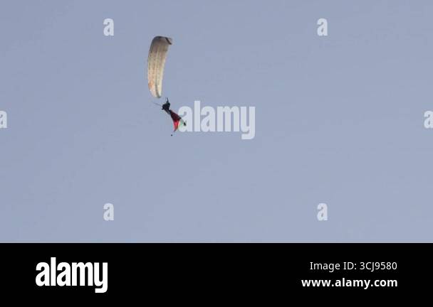 A paraglider flies in a clear blue sky, carrying a large Palestinian ...