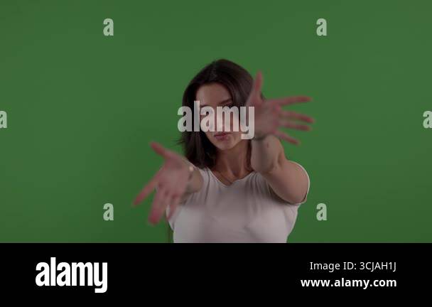 Young woman making a reach out gesture with hands on a green screen ...