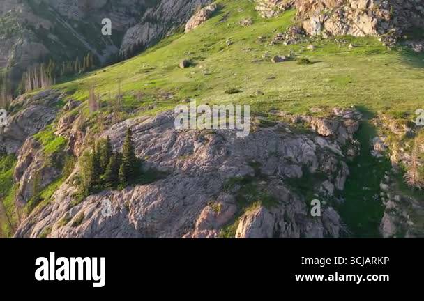 Warm sunlight streaming across verdant mountain slope, revealing rocky ...