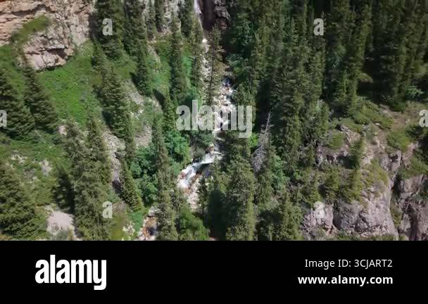 Powerful waterfall cascading down steep rocky cliff, surrounded by ...