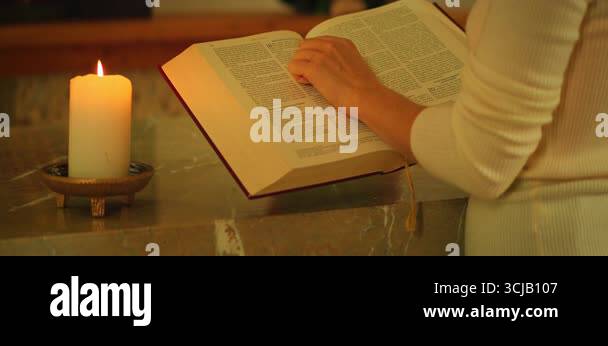 Woman reading Bible near lit candle on church altar indoors Stock Video ...
