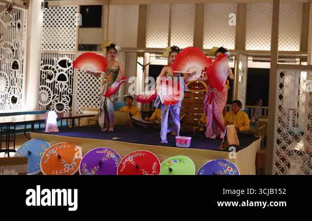 Dancers in vibrant costumes perform a traditional dance with fans on a restaurant stage ...