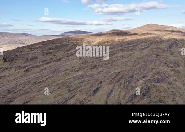 A sweeping aerial view of desolate, rocky highlands under a pale sky ...