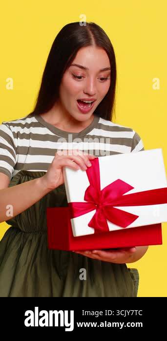 Young woman opening birthday gift box with surprised and happy ...