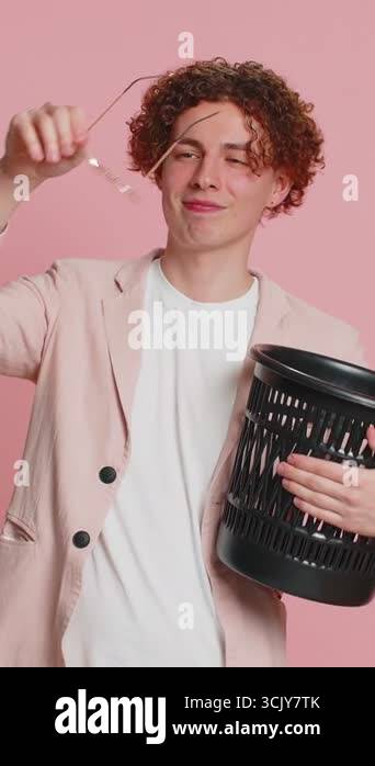 Caucasian young man with curly hair taking off throwing out glasses ...