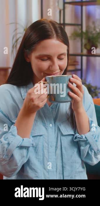 Lovely smiling happy Caucasian young woman drinking a cup of warm ...