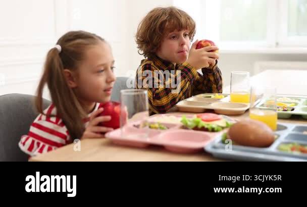 Little kids eating lunch at wooden table in school canteen Stock Video ...