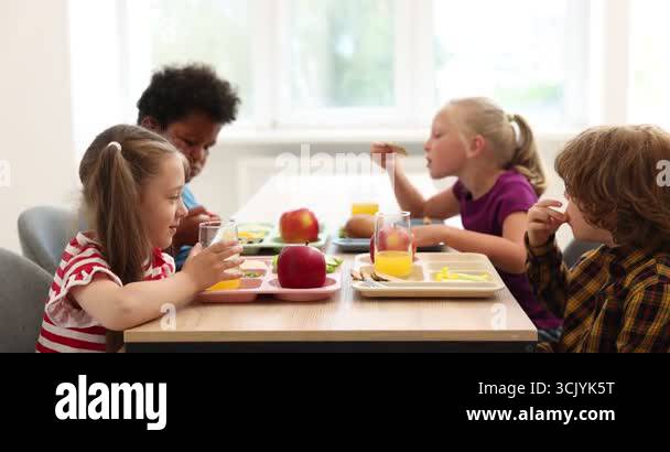 Little kids eating lunch at wooden table in school canteen Stock Video ...