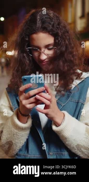 Smiling tired exhausted young teenage girl using smartphone typing text ...