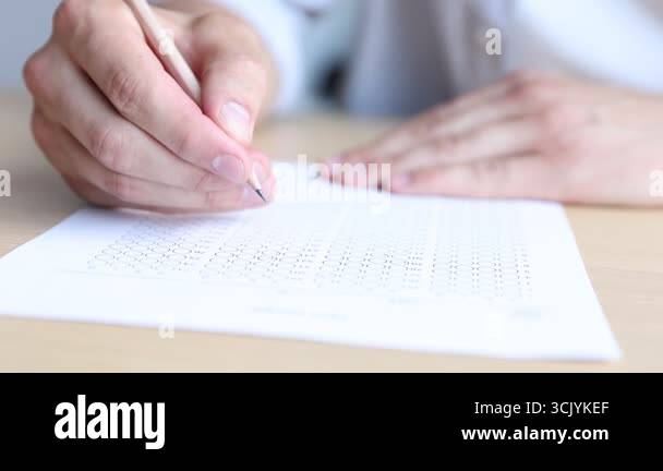 Student filling out multiple choice test at table in class, closeup ...