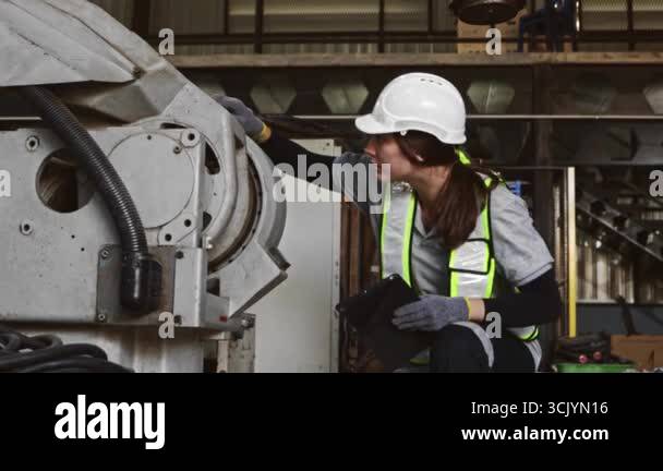 Female robot engineer holding laptop walks inspect robot hydraulic TIG ...