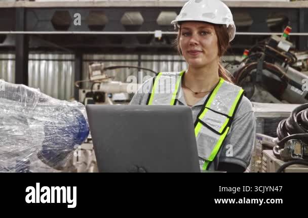 Female robot engineer holding laptop walks inspect robot hydraulic TIG ...