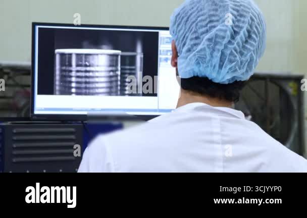 Male QC worker looks at the screen controlling the metal detector ...