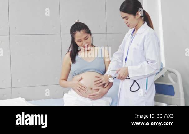 Obstetrician using stethoscope to check fetal health in mother's womb ...