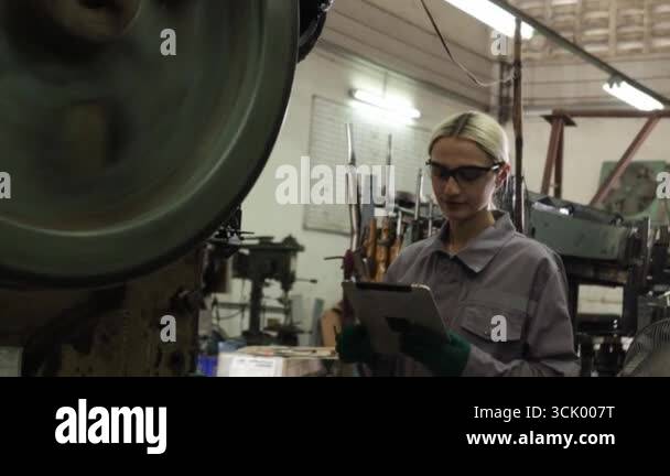 Female lathe operator wearing safety glasses protect against scrap ...