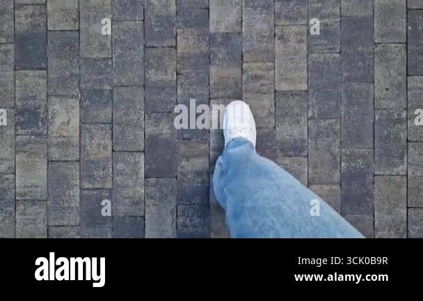 Close-up of female legs in white sneakers and jeans walking along a ...