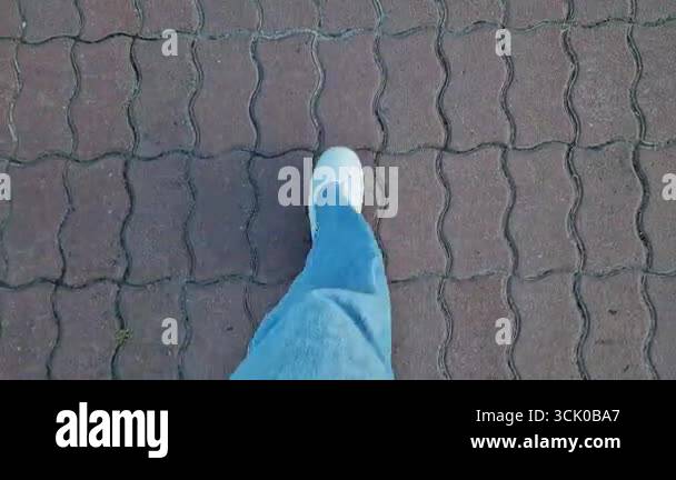 Close-up of female legs in white sneakers and jeans walking along a ...