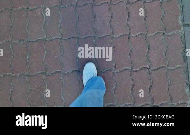Close-up of female legs in white sneakers and jeans walking along a ...