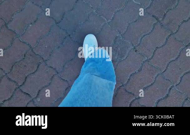 Close-up of female legs in white sneakers and jeans walking along a ...