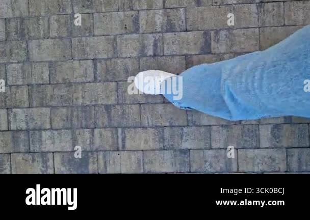 Close-up of female legs in white sneakers and jeans walking along a ...