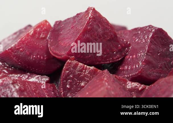 Boiled red beetroot cut into pieces rotates on grey background, close ...