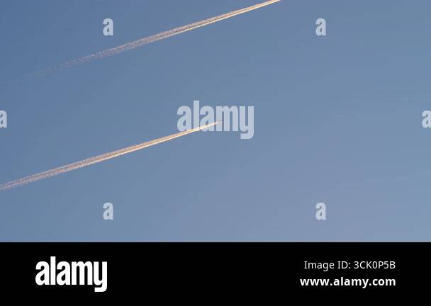Three airplanes are flying high in the clear blue sky, leaving white ...