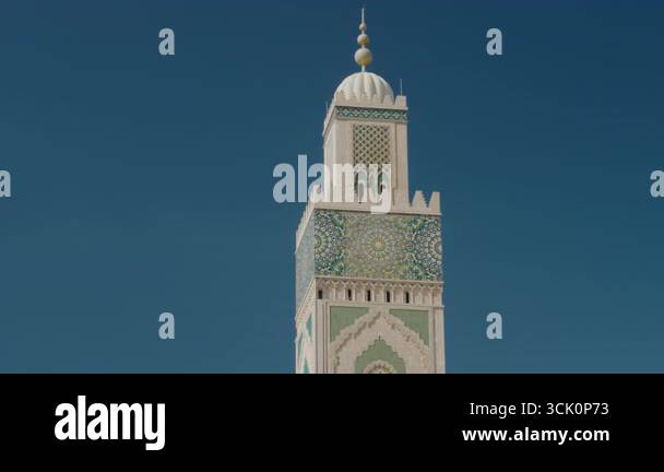 The Hassan II Mosque Minaret against a Deep Blue Sky. The ornately detailed tiled patterns and ...
