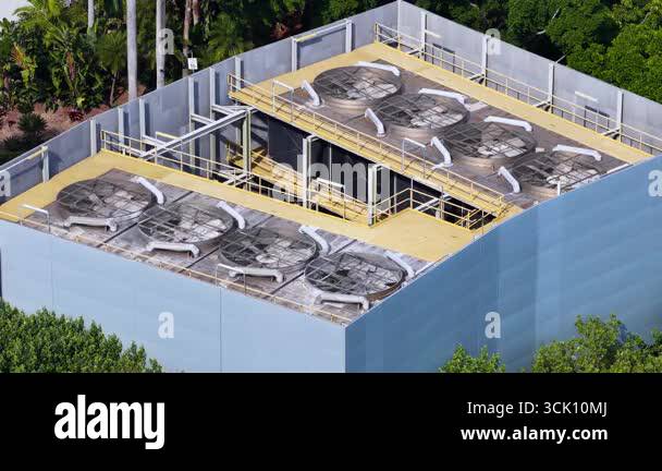 Aerial footage of a cooling tower with rotating fans, surrounded by ...