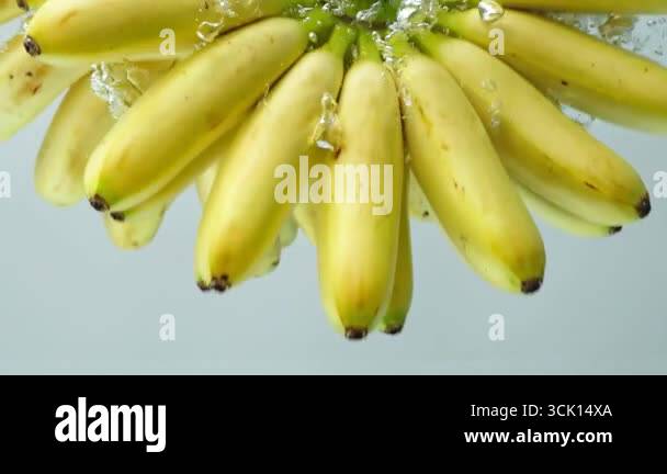 Bunch of mini bananas submerged in water with many bubbles, slow motion ...