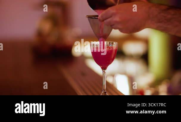 Pouring alcohol cocktail. Bright drink. Bartender hand straining pink ...
