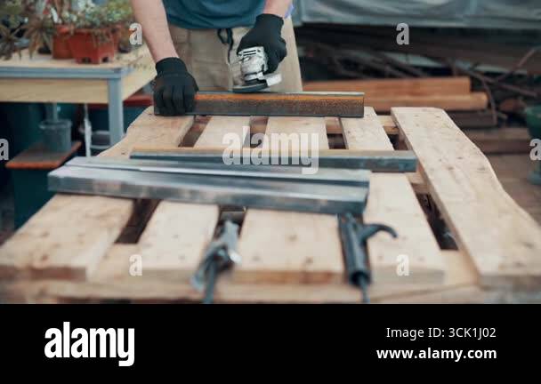 A worker is grinding rust off a steel part with an angle grinder. Close ...