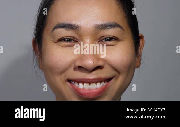A close-up portrait of an Asian woman smiling happily, showing teeth ...