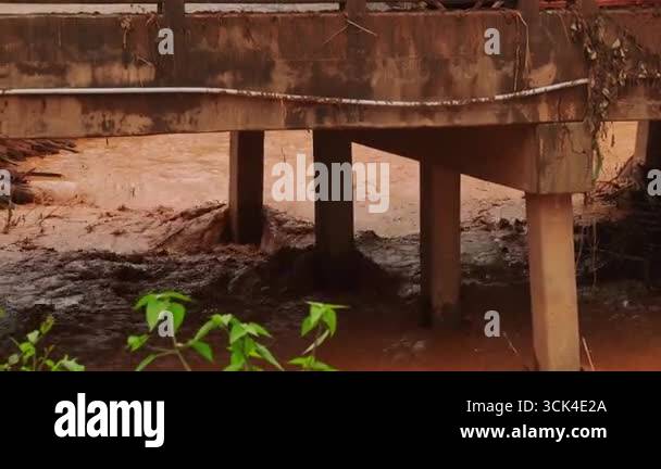 Floodwater flowing under damaged concrete bridge after heavy rain ...