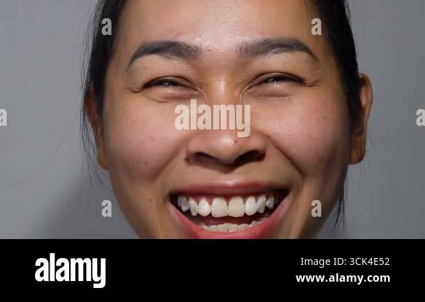 A close-up portrait of an Asian woman smiling happily, showing teeth ...