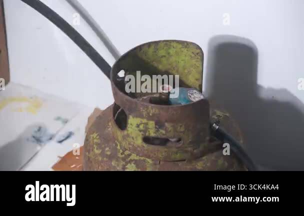 An Asian man is trying hard to install a green gas cylinder, showing ...