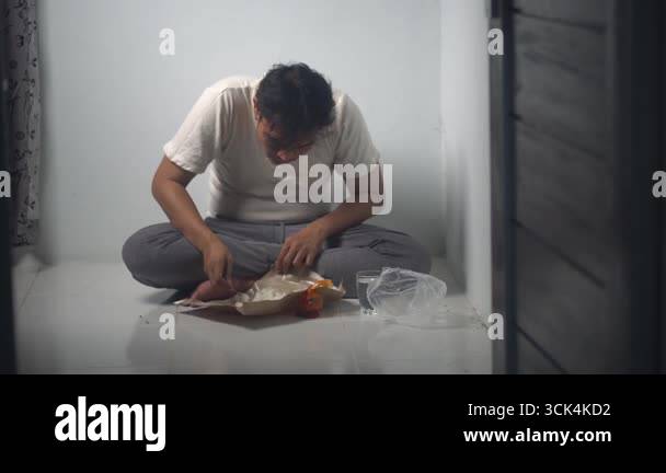 An Asian man in shabby clothes is eating rice given to him, focusing on ...