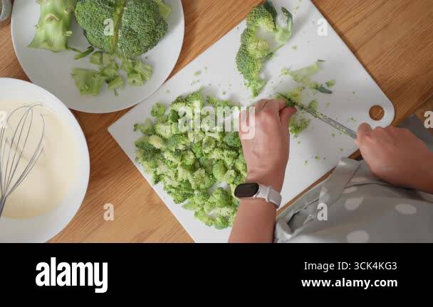 A woman's hands meticulously cut fresh green broccoli florets into ...