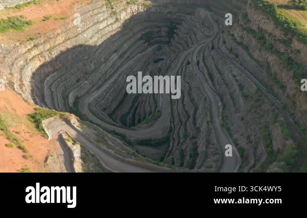 Excavation pit spiraling downward with winding roads shaping mineral ...