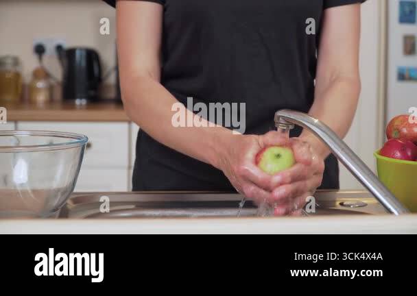 Rinsing whole apple under faucet preparing homemade compote. Washing ...
